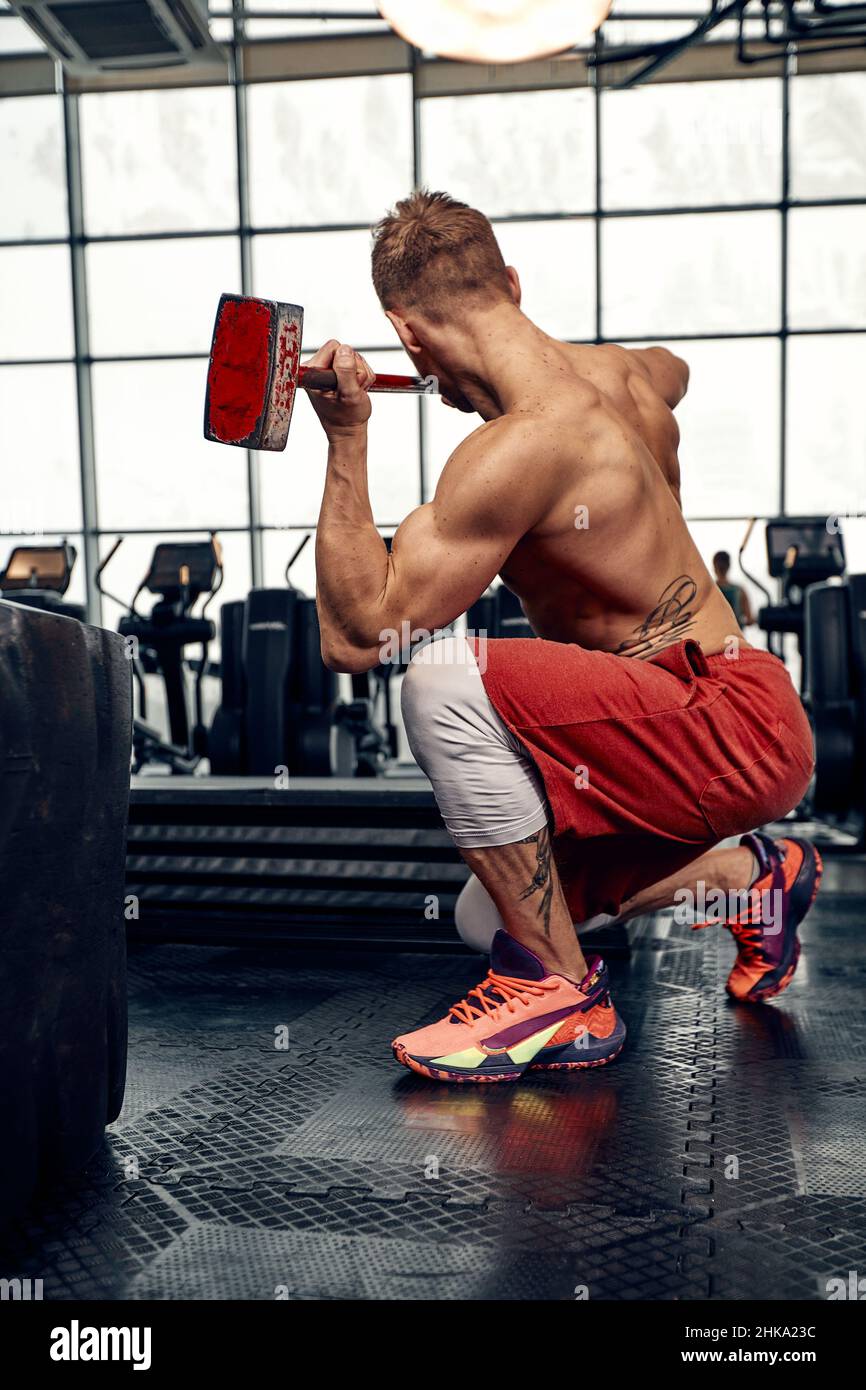 Strength concept. Male athlete using hammer during fitness workout ...