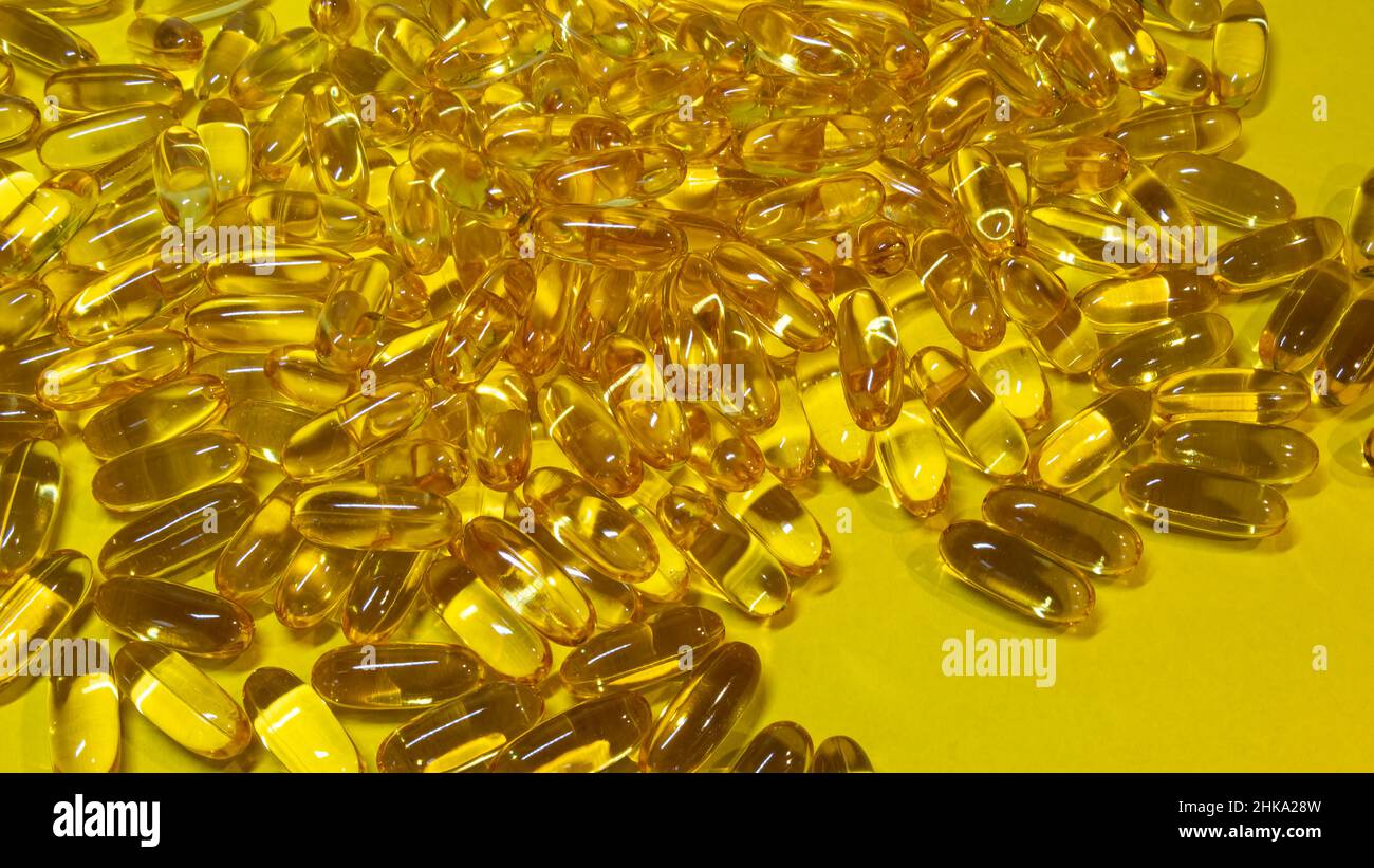 Big capsules with a fish oil, a heap of golden jelly pills scattered on ...