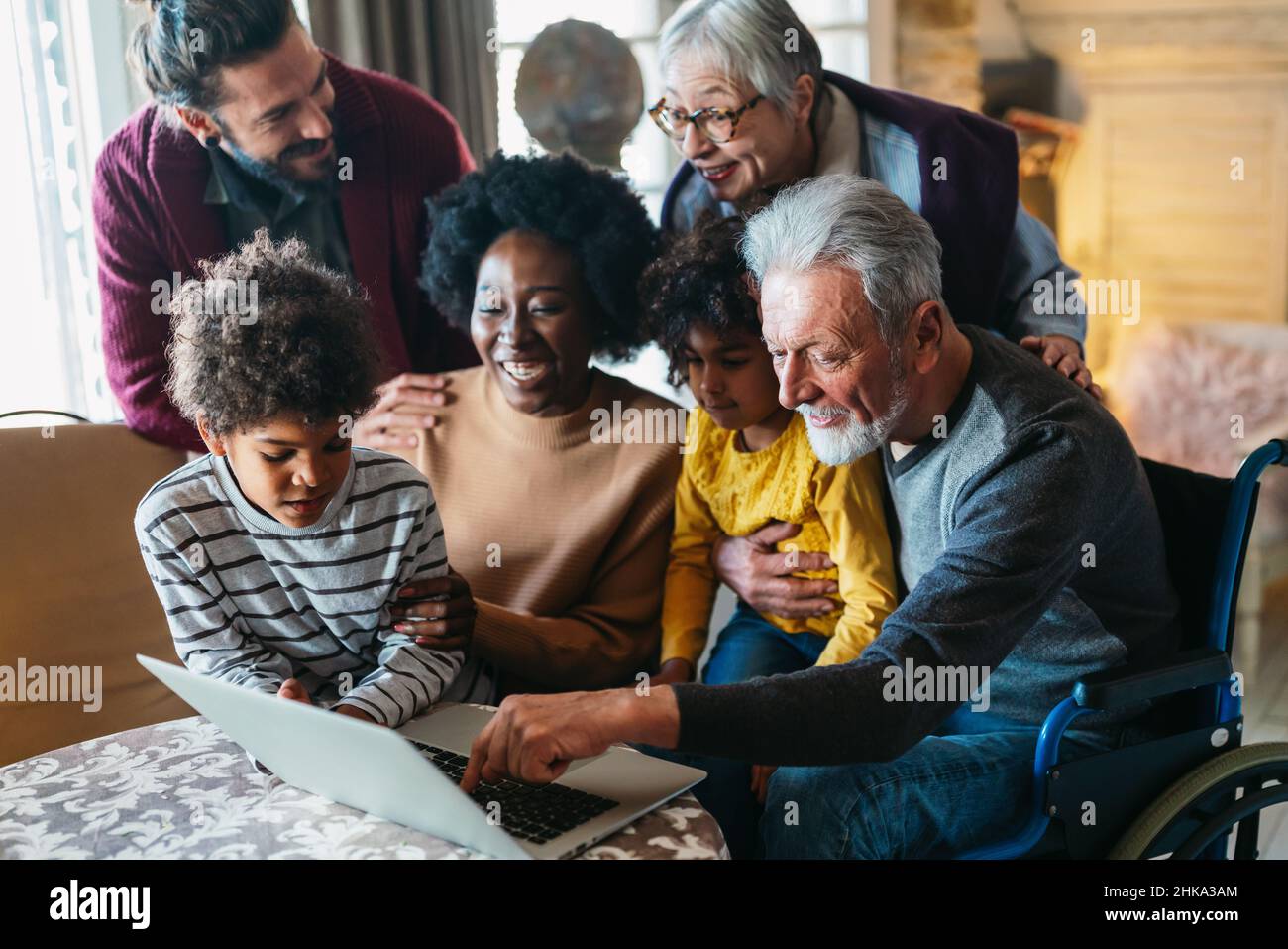Portrait of a happy multigeneration family using electronic devices at ...