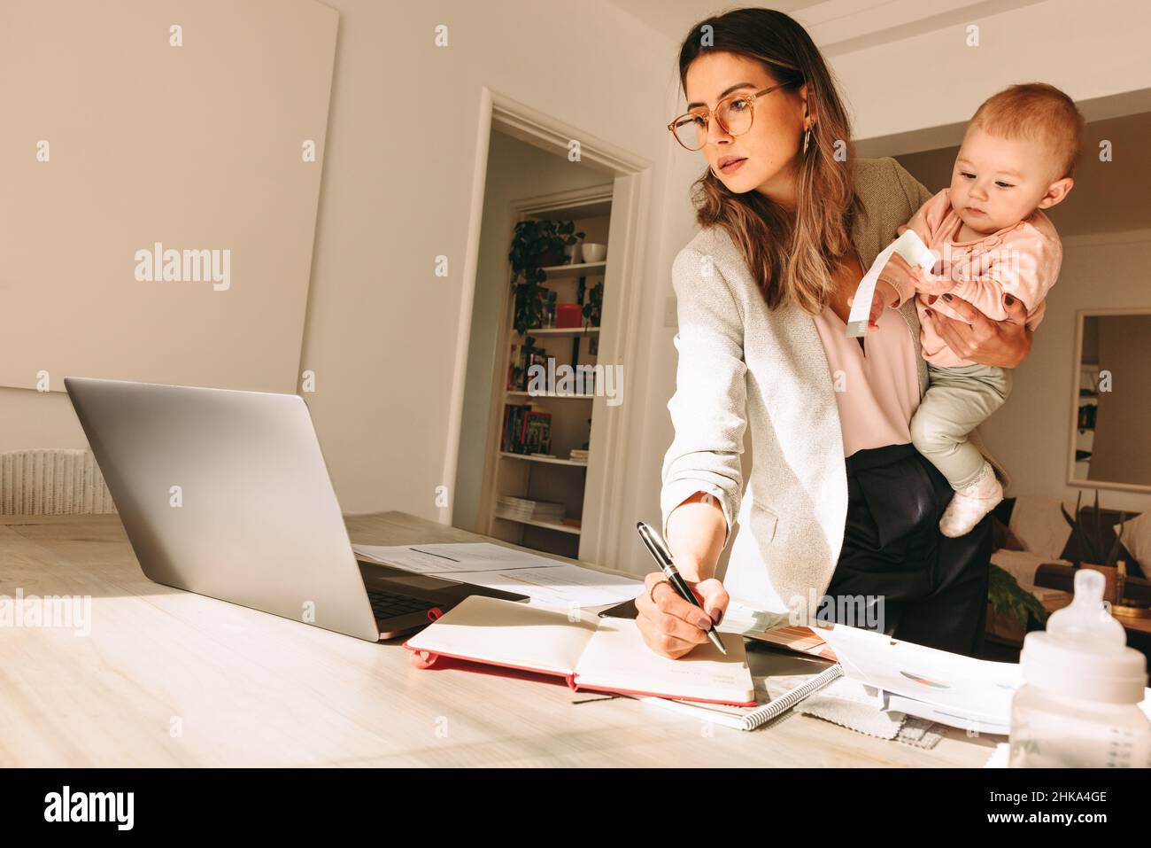 Multitasking mom working on a new project in her home office. Working ...