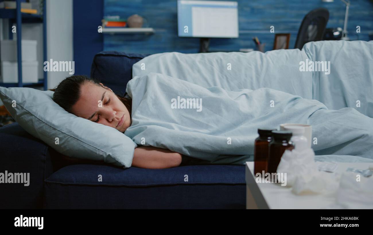 Close up of ill adult laying wrapped in blanket on sofa while having ...