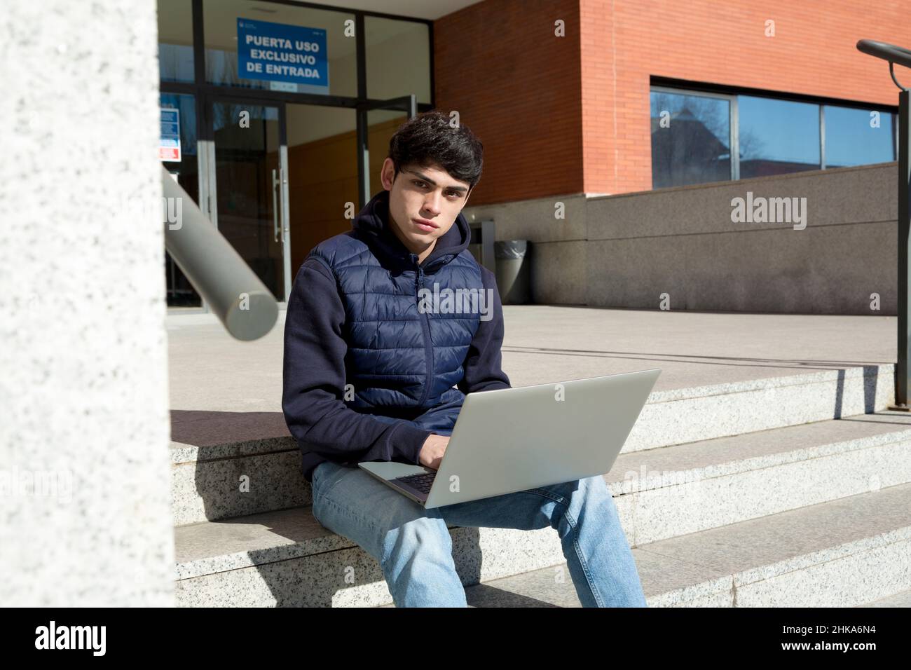 college student boy using laptop computer sitting on university stairs ...
