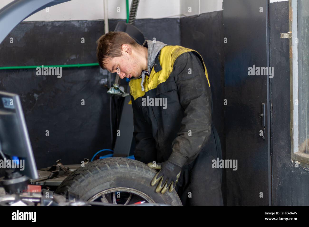 Young mechanician changing car wheel in auto repair shop using ...