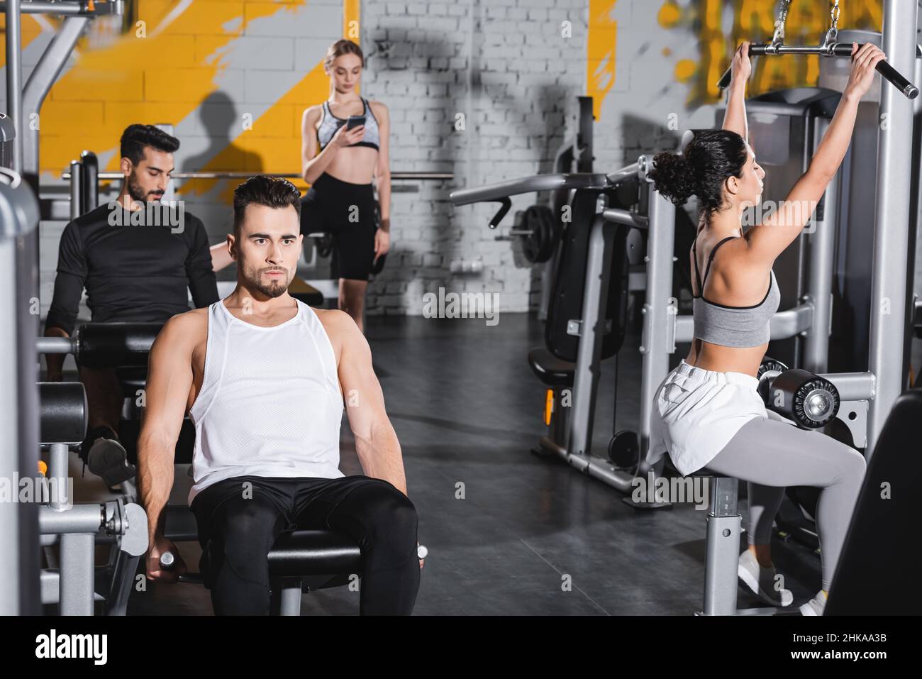 Interracial young people working out with equipment in sports center ...