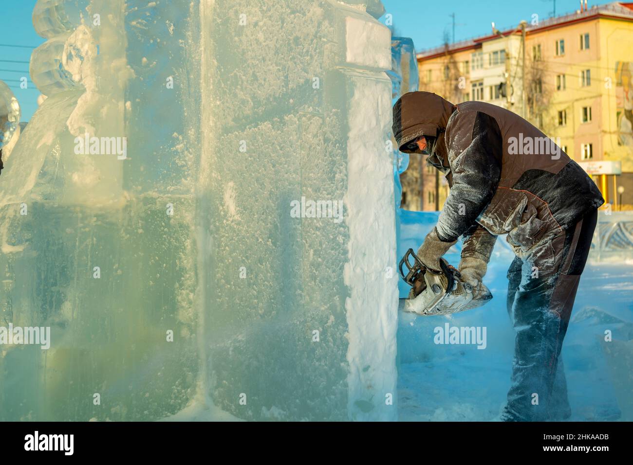 The sculptor cuts an ice figure out of ice by a chainsaw for Christmas ...