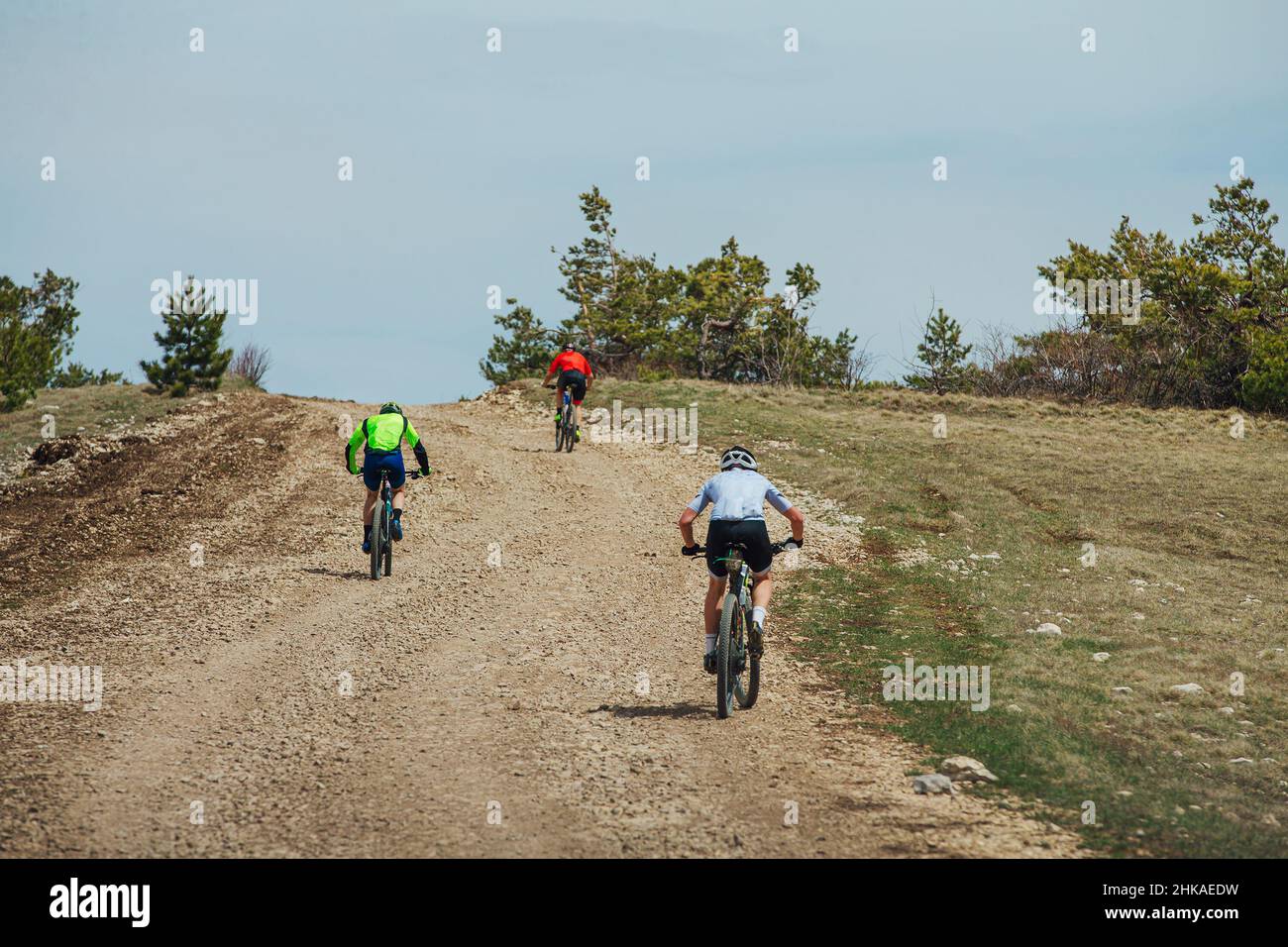 three athletes cyclists riding uphill on mountain bike Stock Photo - Alamy