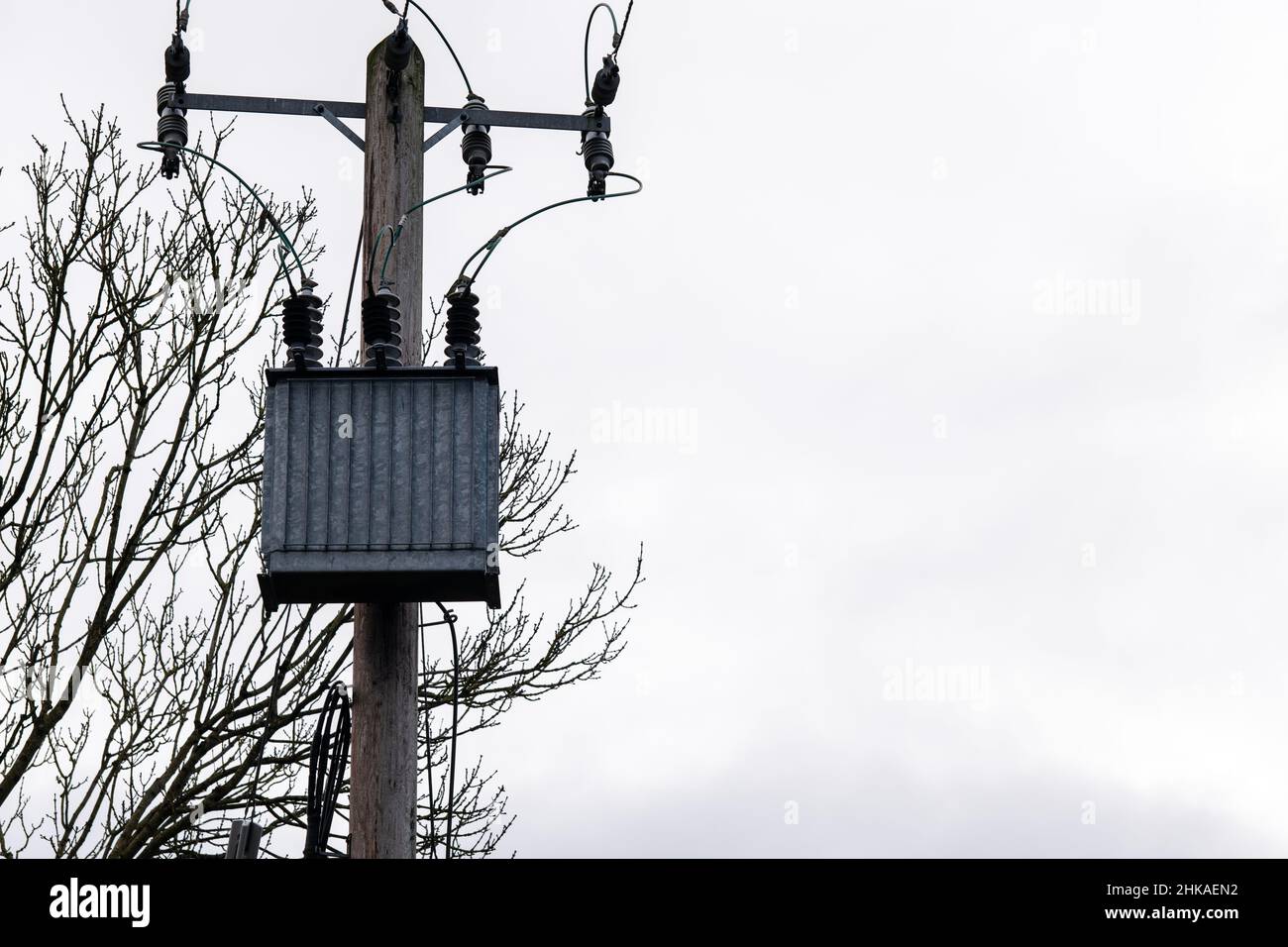 External transformer suspended on a wooden power bracket into electric ...
