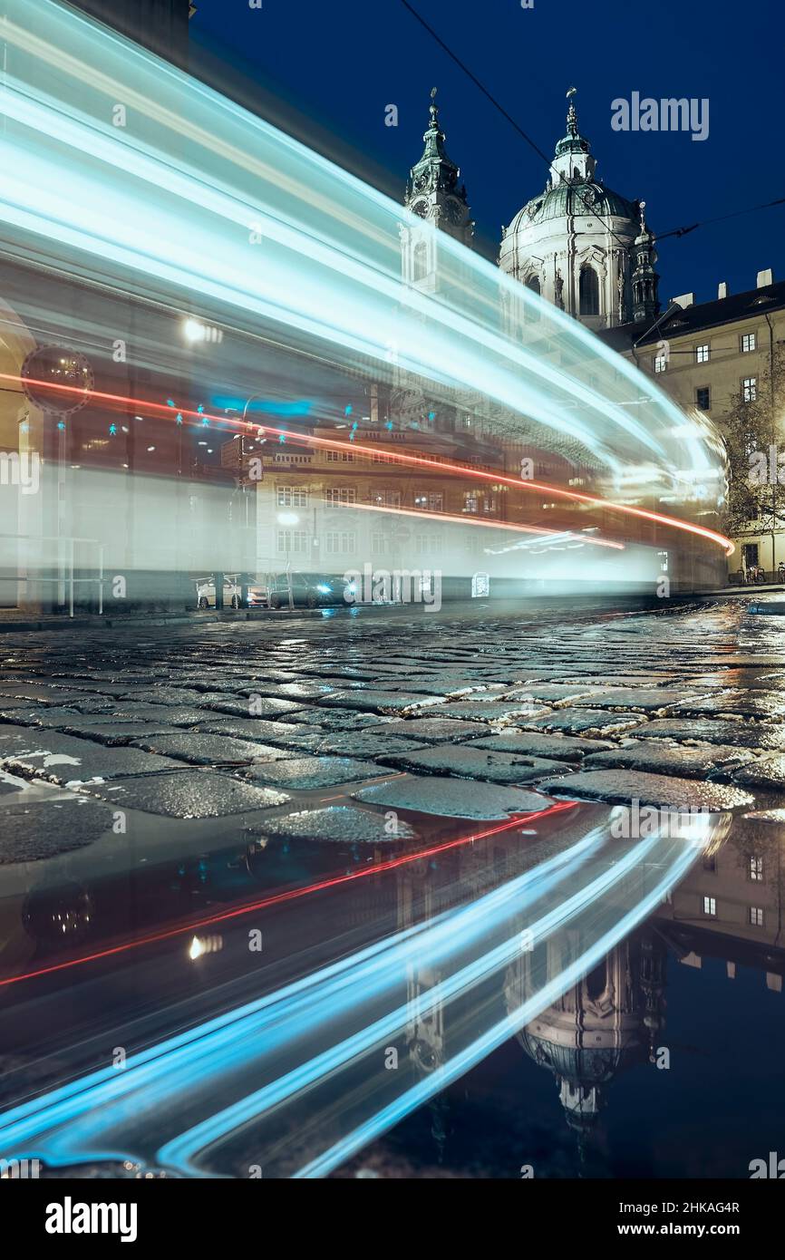 Light trail of tram passing between historical buildings. Reflection in ...