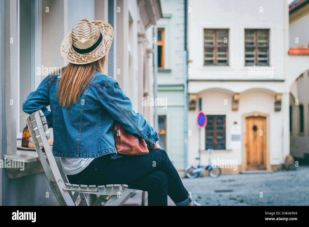 Woman sitting on chair in the street of European old town. Female ...