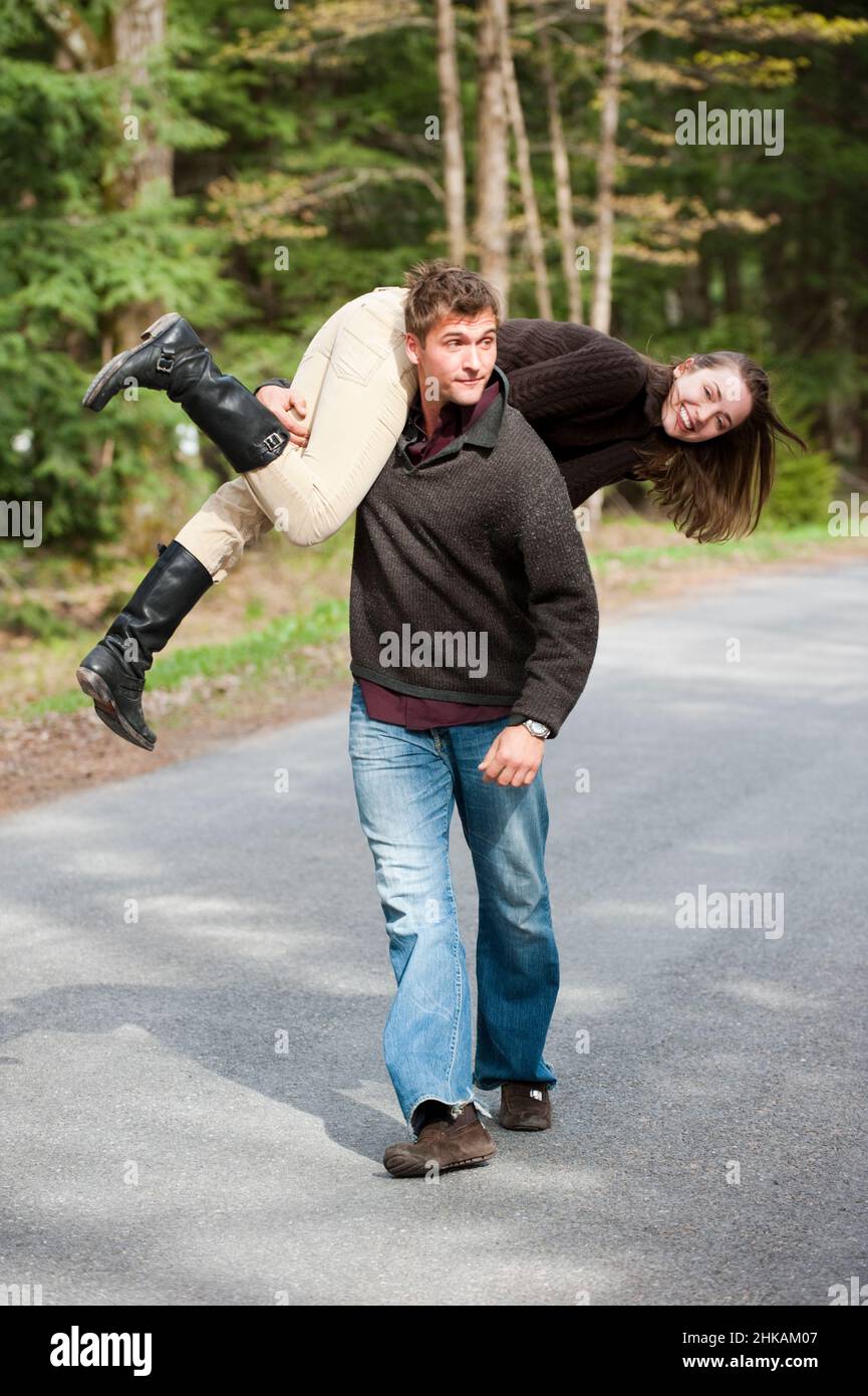 Young man giving piggy back ride to young woman on road Stock Photo - Alamy