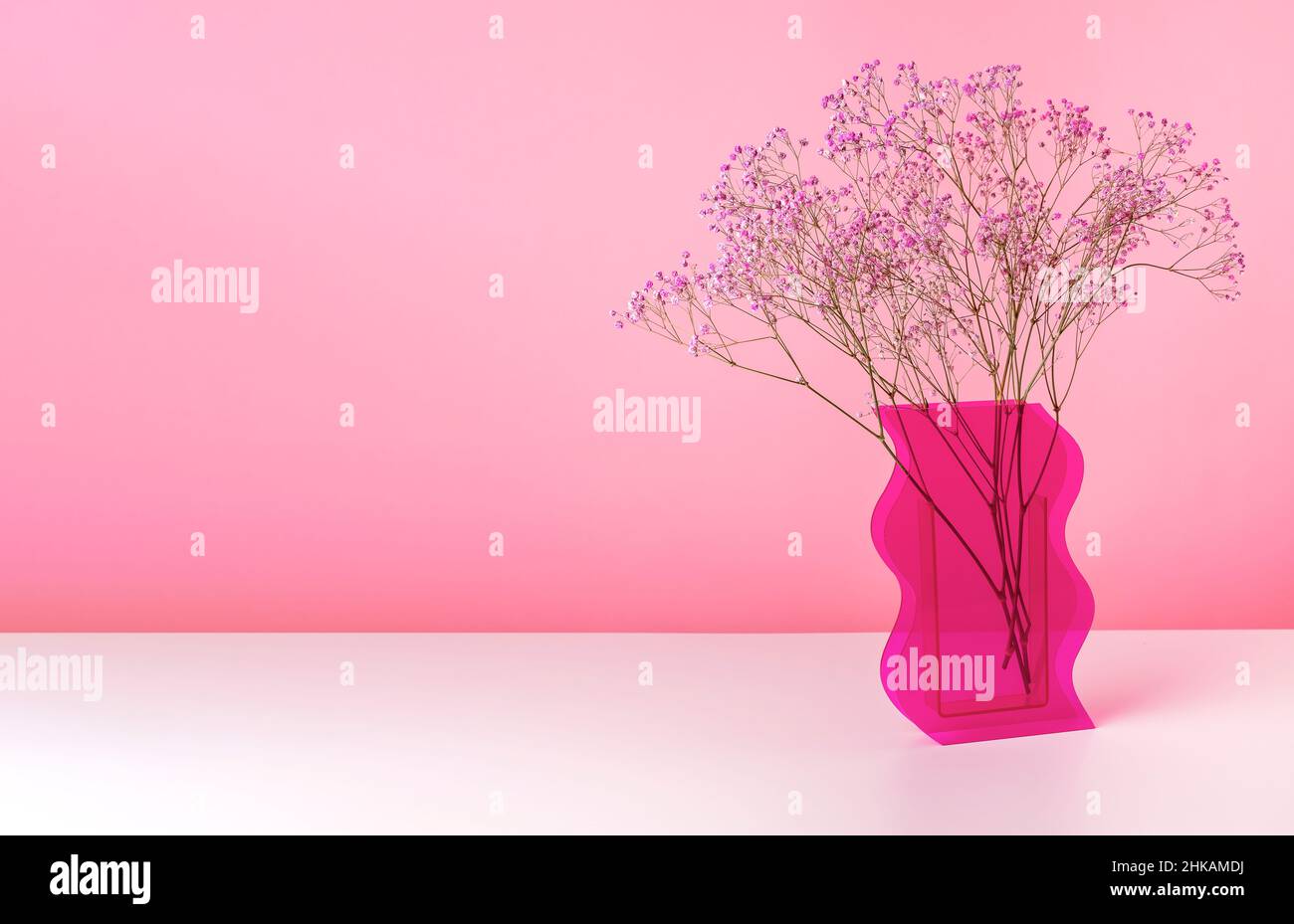 Tender flowers in vase on table over pink banner with copy space for ...