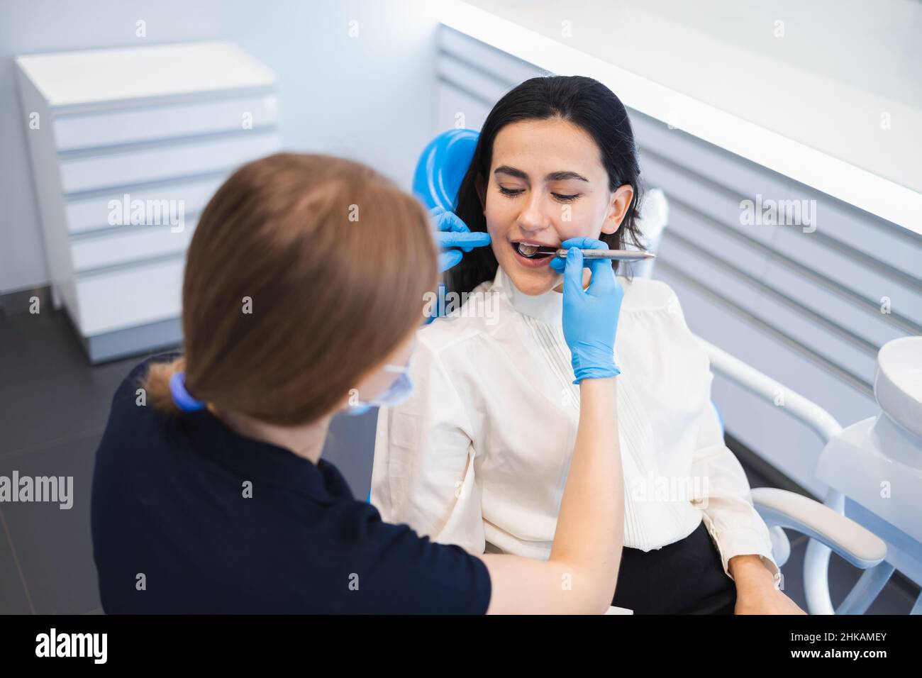 Dentist examining female patient's teeth in modern clinic. Beautiful ...