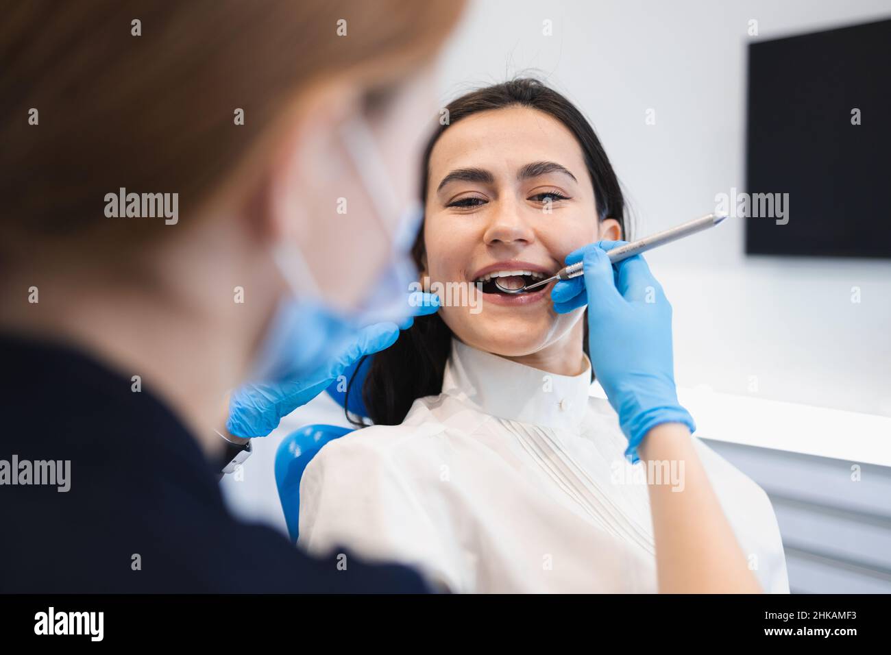 Pretty brunette woman at the dentist appointment. Female patient treats her teeth in a dental ...