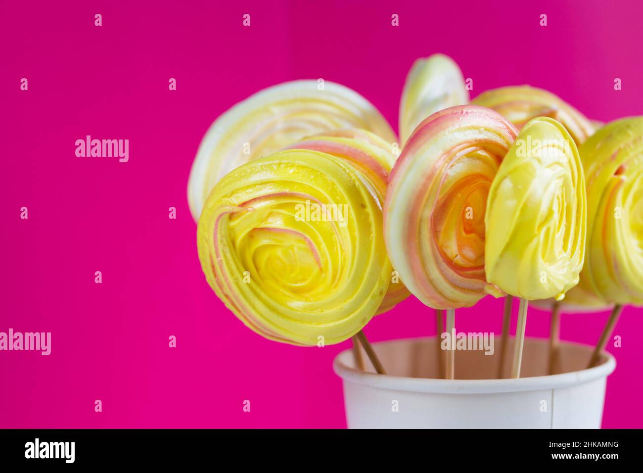 Decorative meringues on sticks in white plastic glass on the purple ...