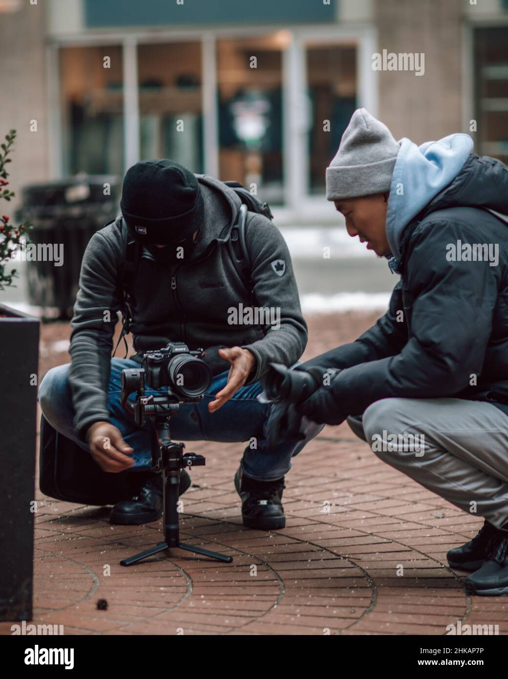 two male photographers squatting down to adjust setup their camera ...