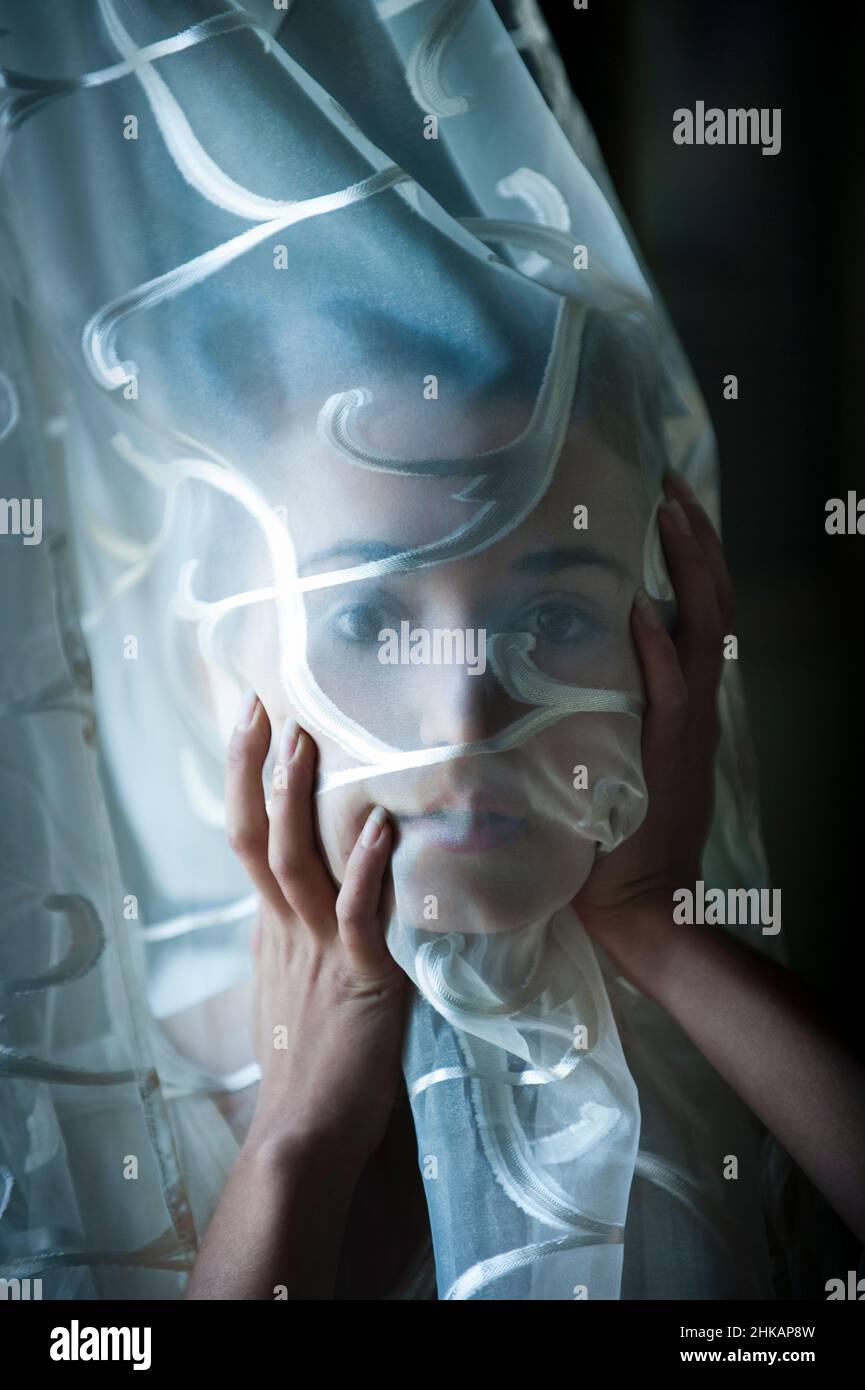 Womans face wrapped in transparent patterned curtain Stock Photo - Alamy