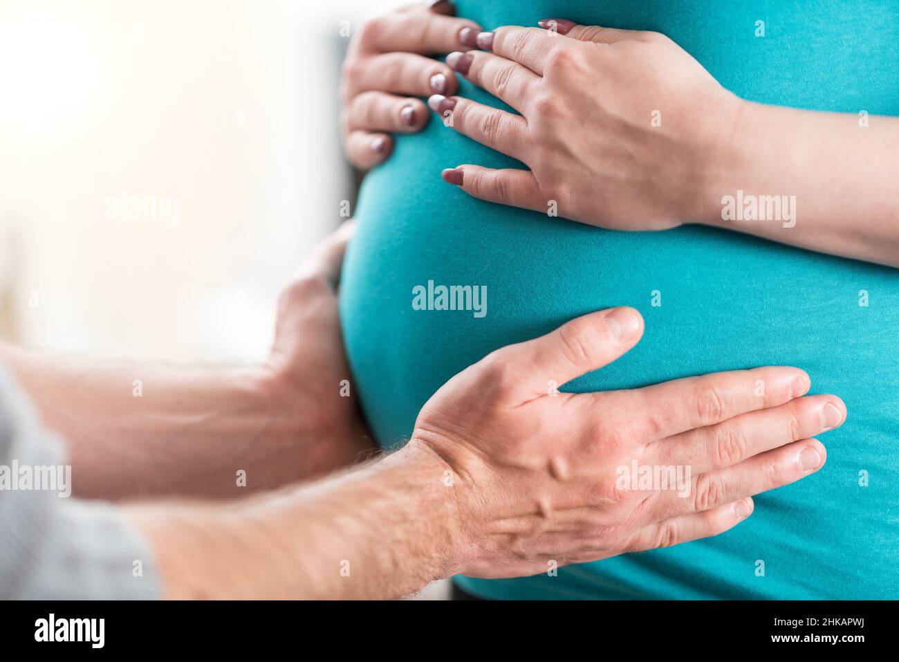 Couple holding hands on pregnant belly Stock Photo - Alamy