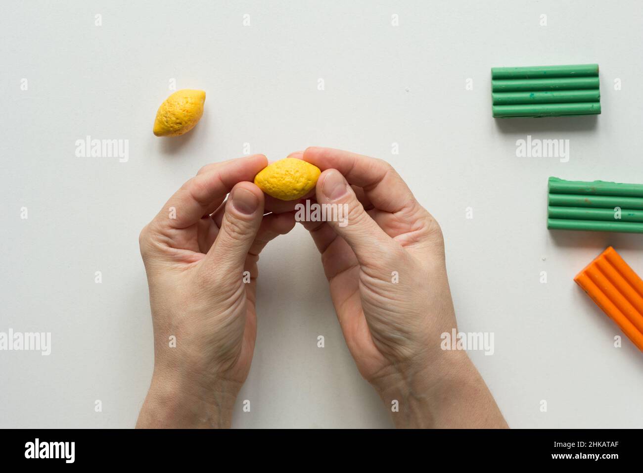 Woman hands holding small lemon made from polymer clay on the white ...