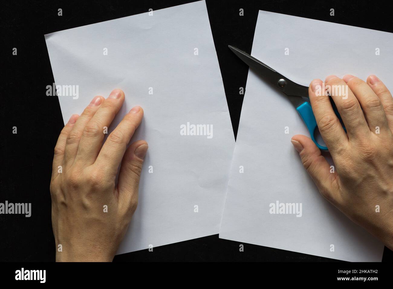 Two pieces of rectangular sheet of paper and woman hands with scissors ...