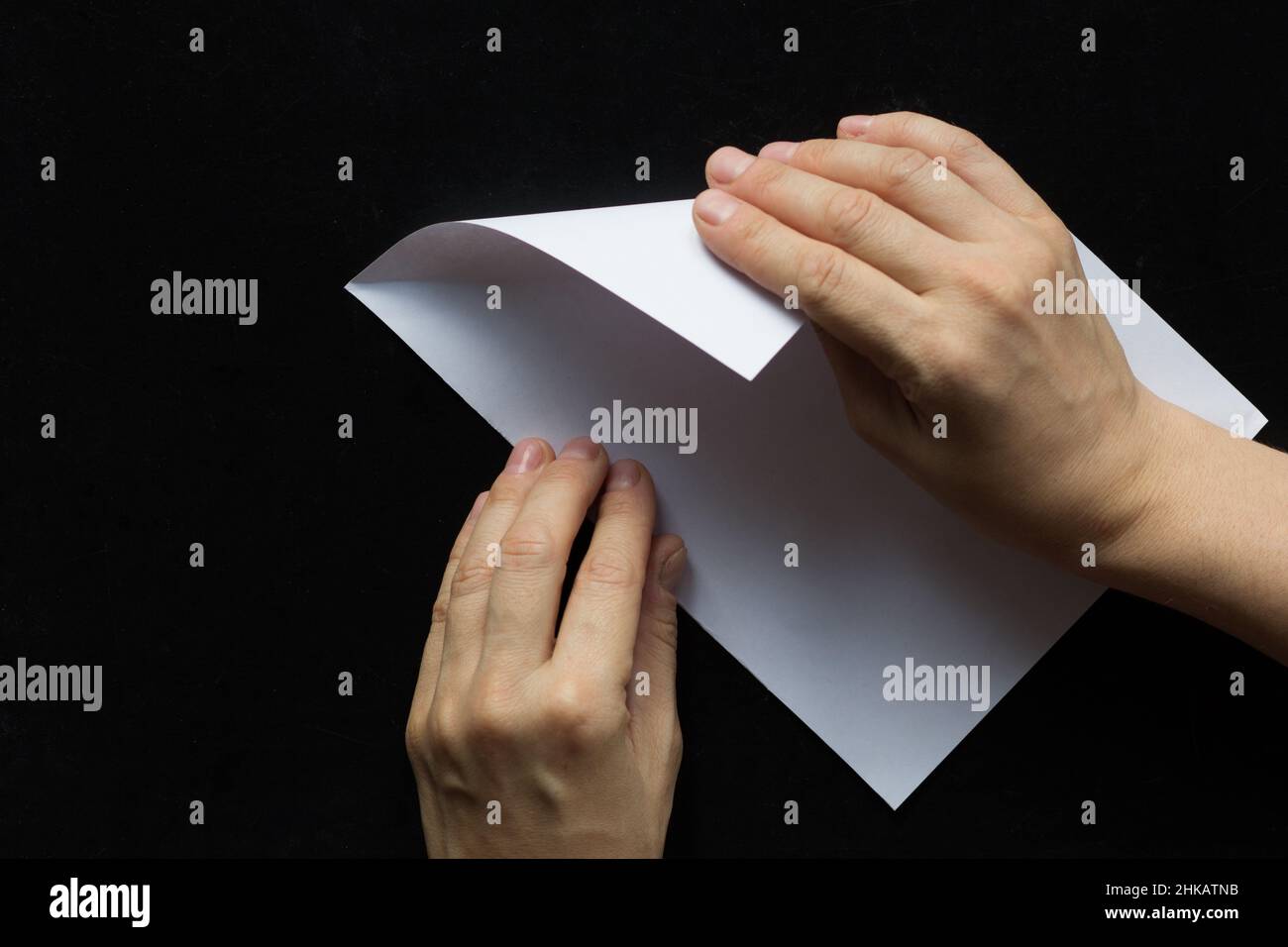 Woman hands folding rectangular sheet of paper to make it square on ...