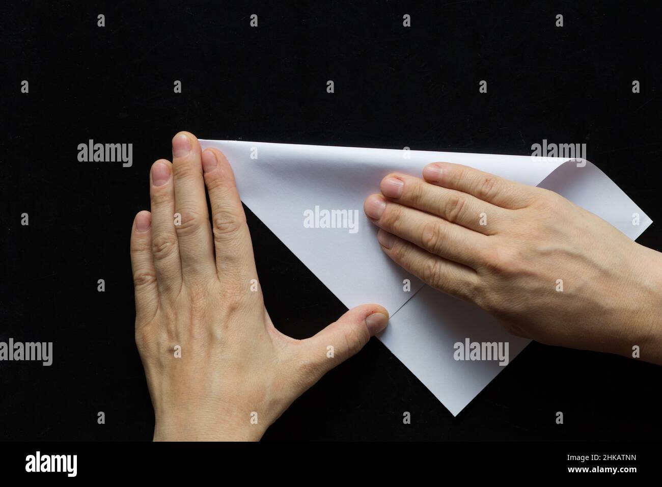 Woman hands folding rectangular sheet of paper to make it square on ...