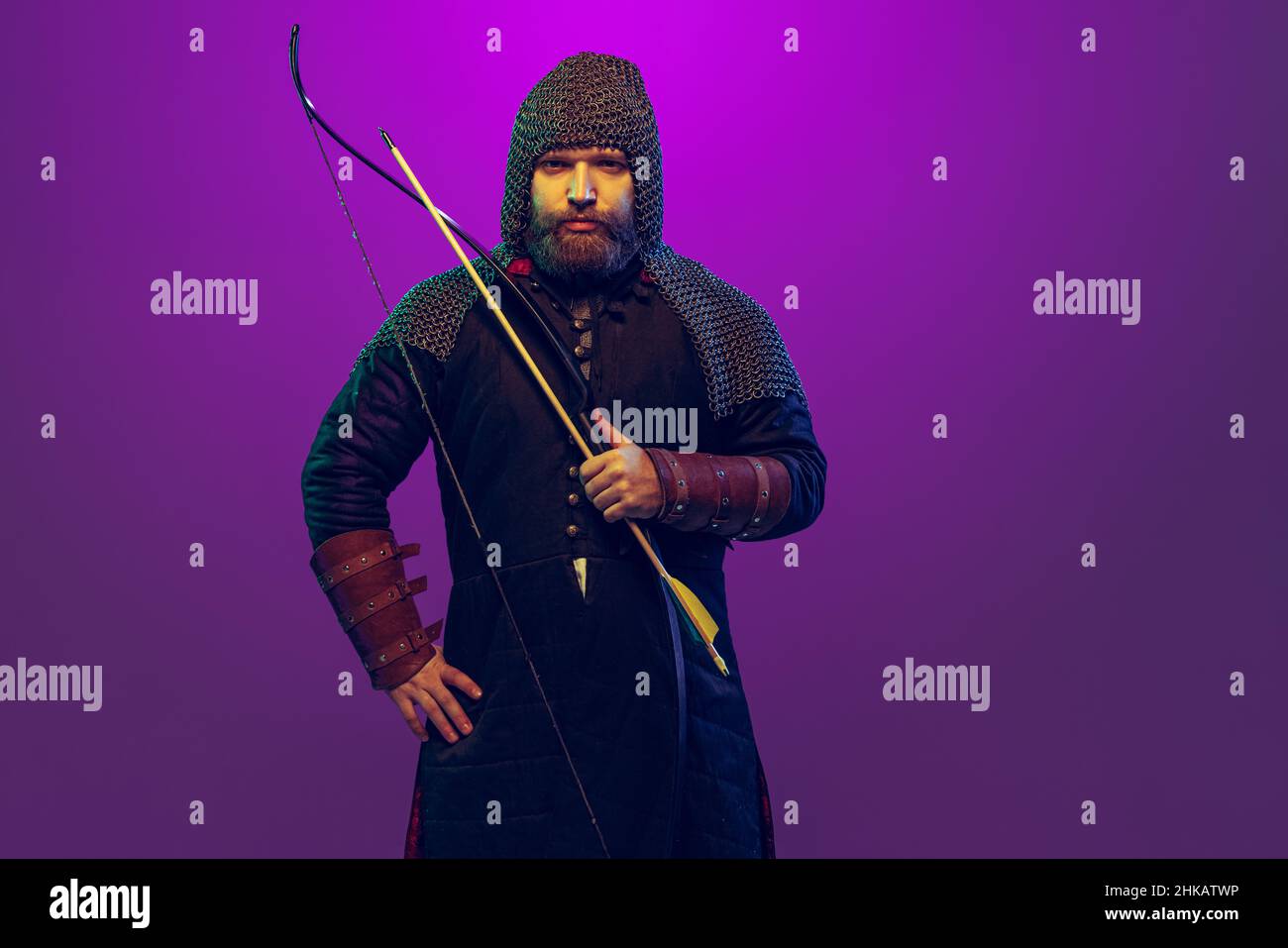 Studio shot of young bearded man in image of medieval warrior, archery ...