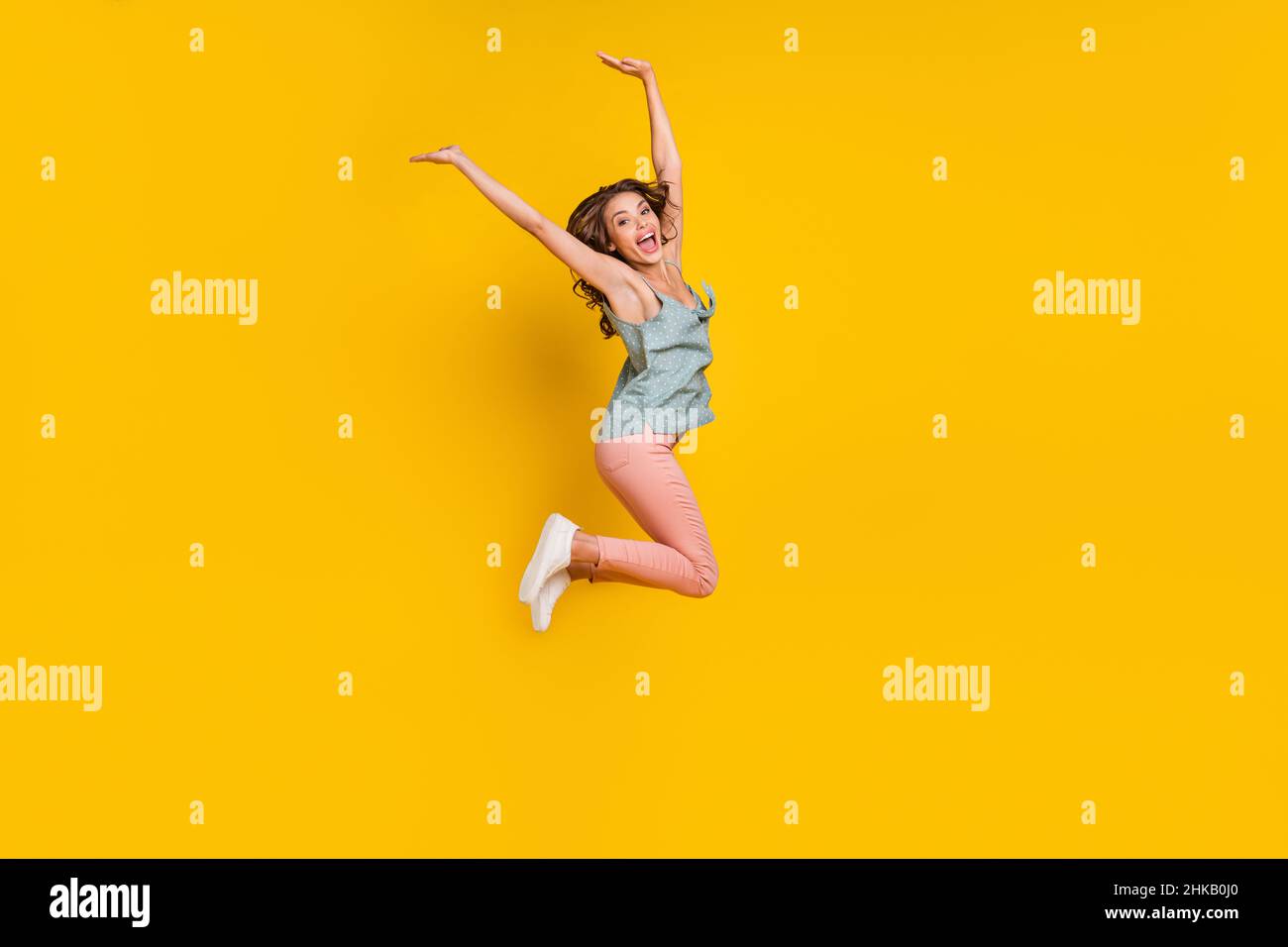 Full size photo of cheerful positive young woman jump up raise hands ...