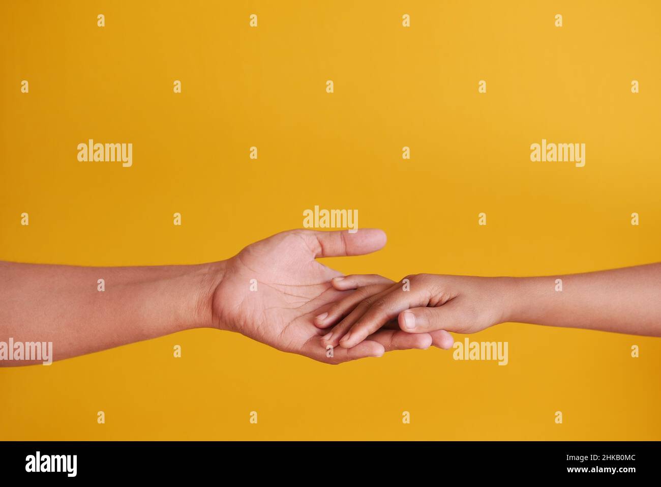 father holding his child boy hand on yellow background Stock Photo - Alamy
