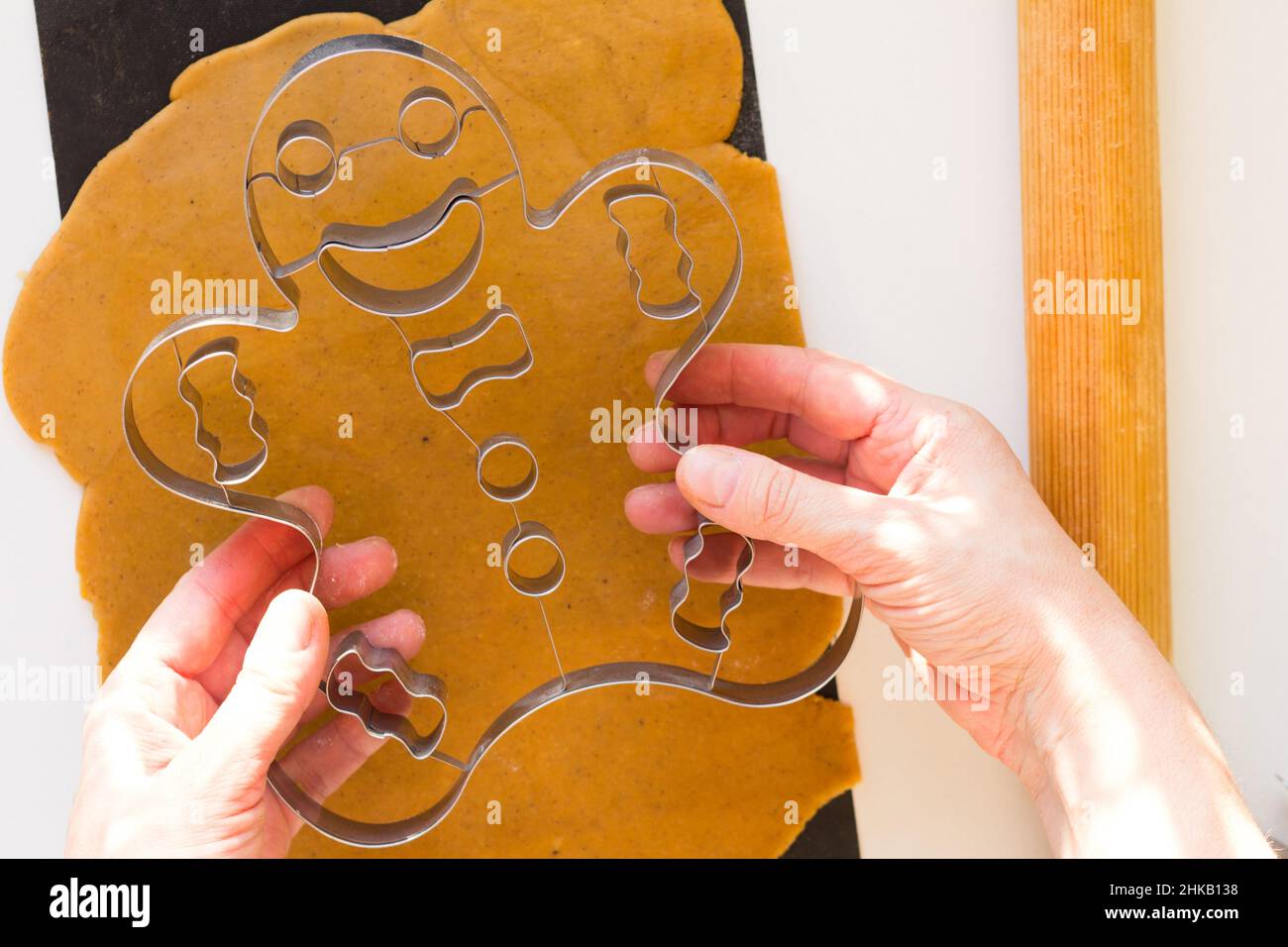 Woman hands holding metal form of gingerbread man before cutting it out ...