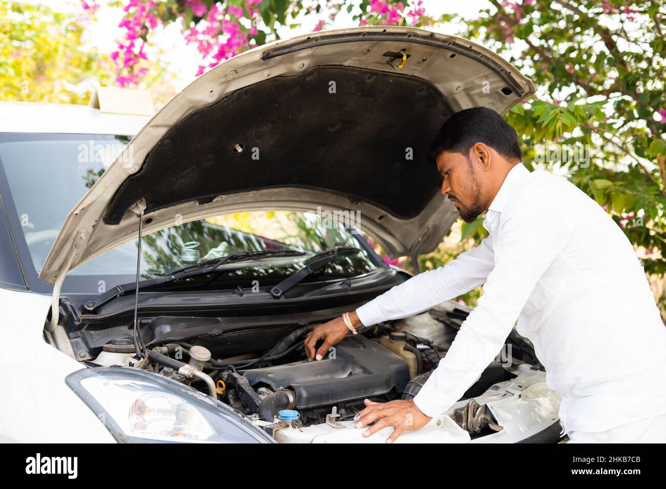 indian cab driver checking or repairing car engine after traveling ...