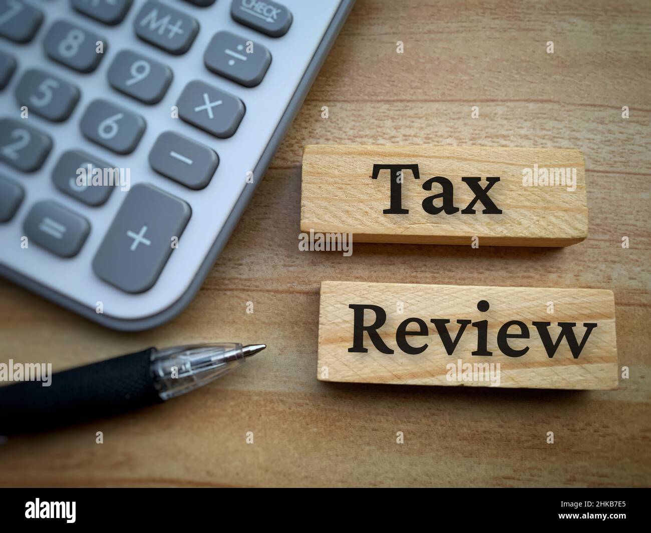 Tax review text on wooden blocks with pen and calculator background ...