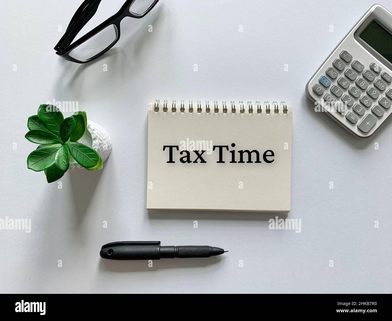 Tax time on notepad with pen, calculator, plant and glasses background ...