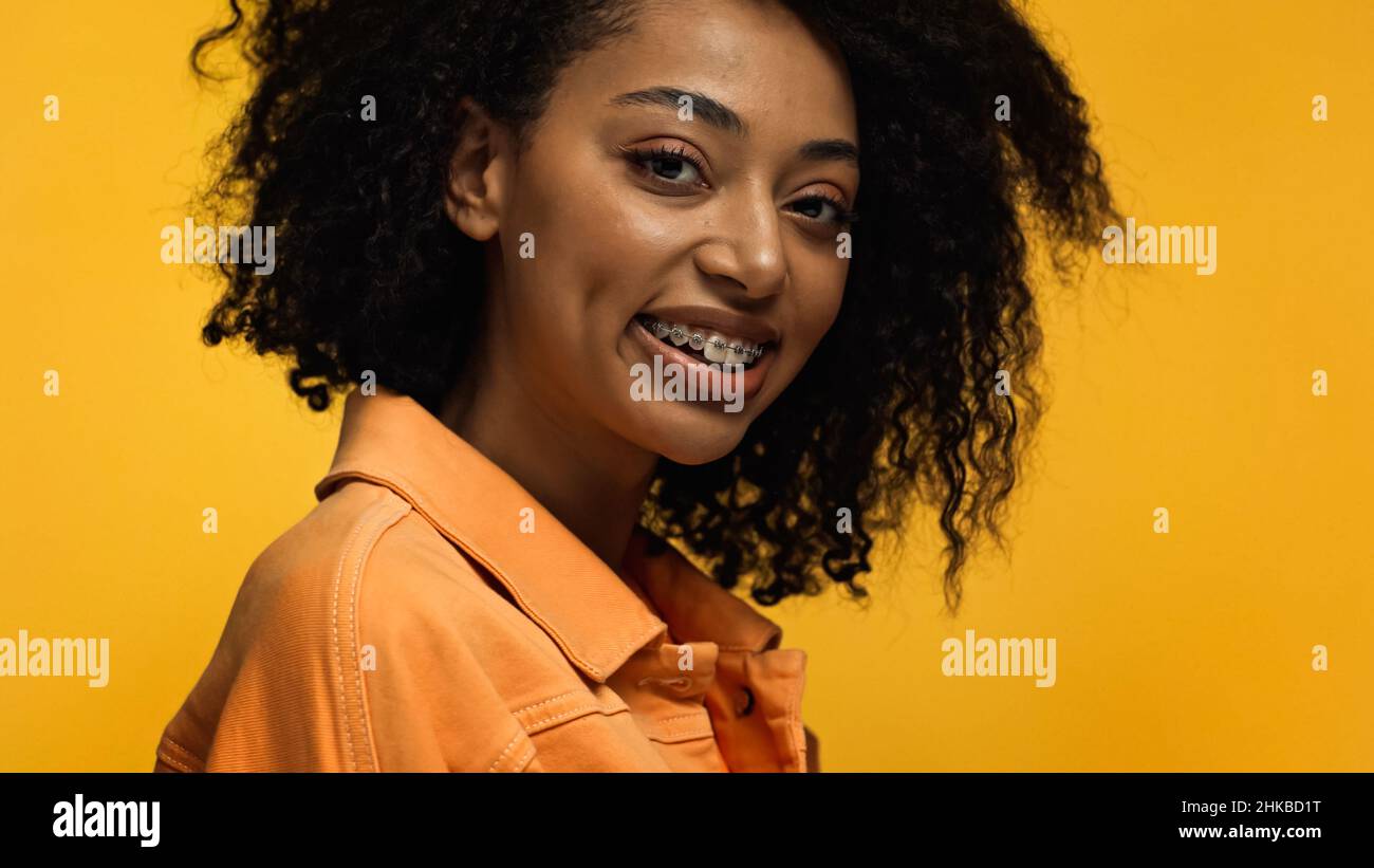 cheerful african american woman with braces smiling isolated on yellow ...