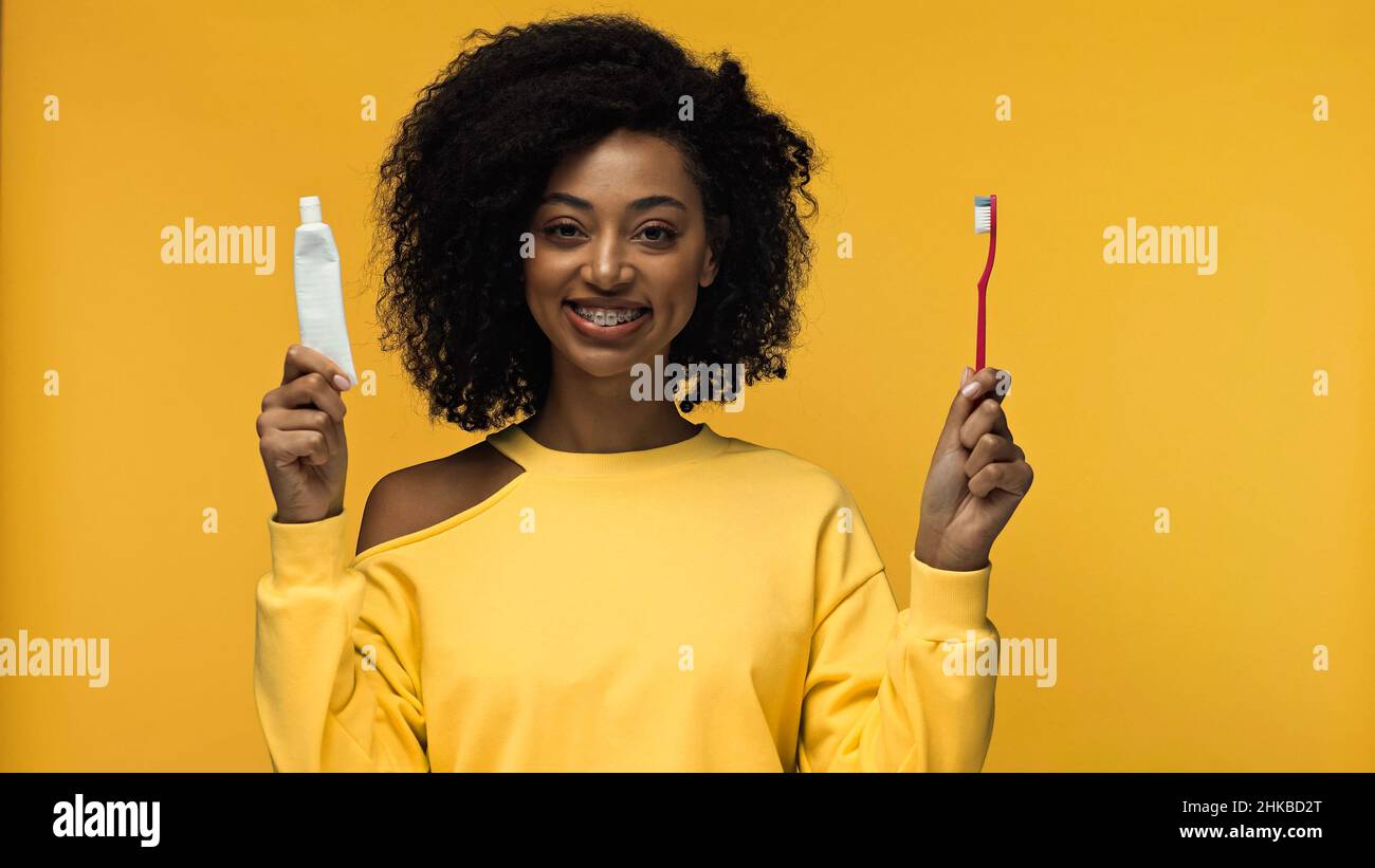 cheerful african american woman with braces holding toothpaste with ...