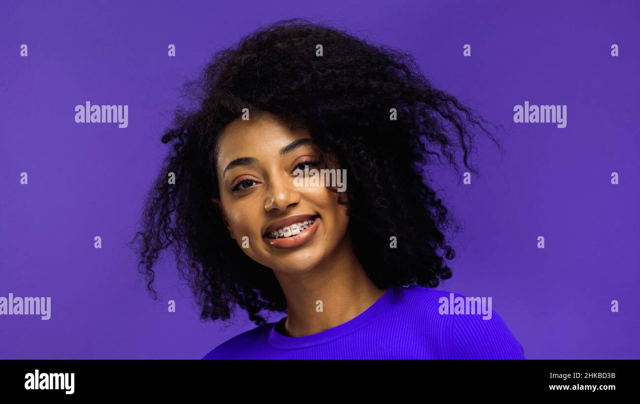 joyful african american woman with braces smiling isolated on purple ...