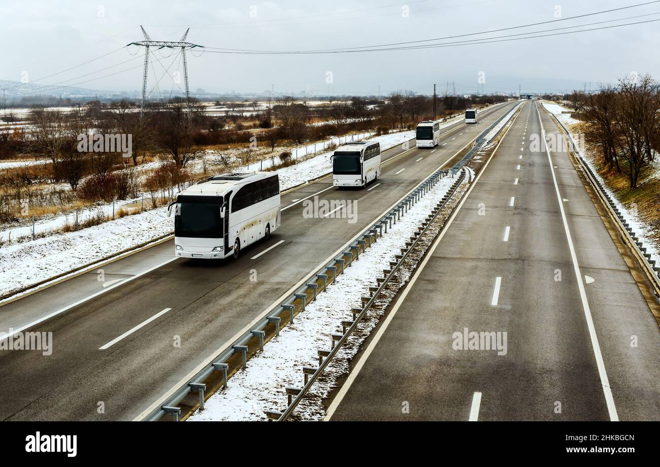 Series of modern White buses traveling on a highway in a snowy winter ...