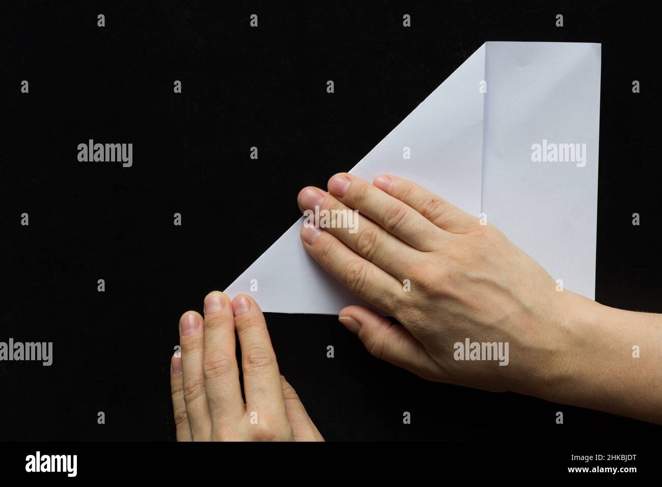 Woman hands folding rectangular sheet of paper to make it square on ...