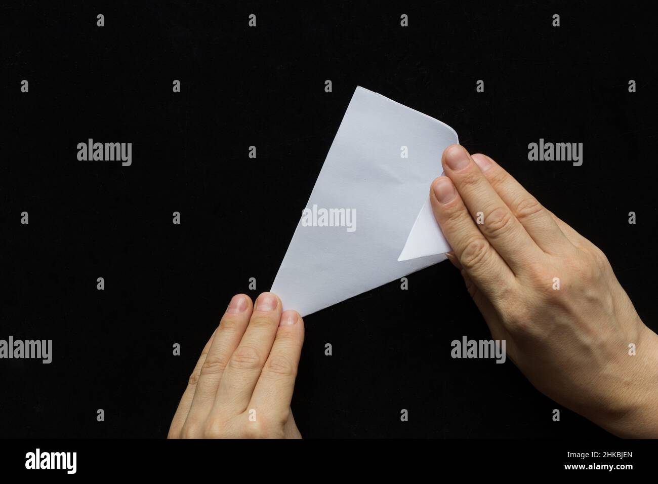 Woman hands folding paper triangle to make smaller one on black ...