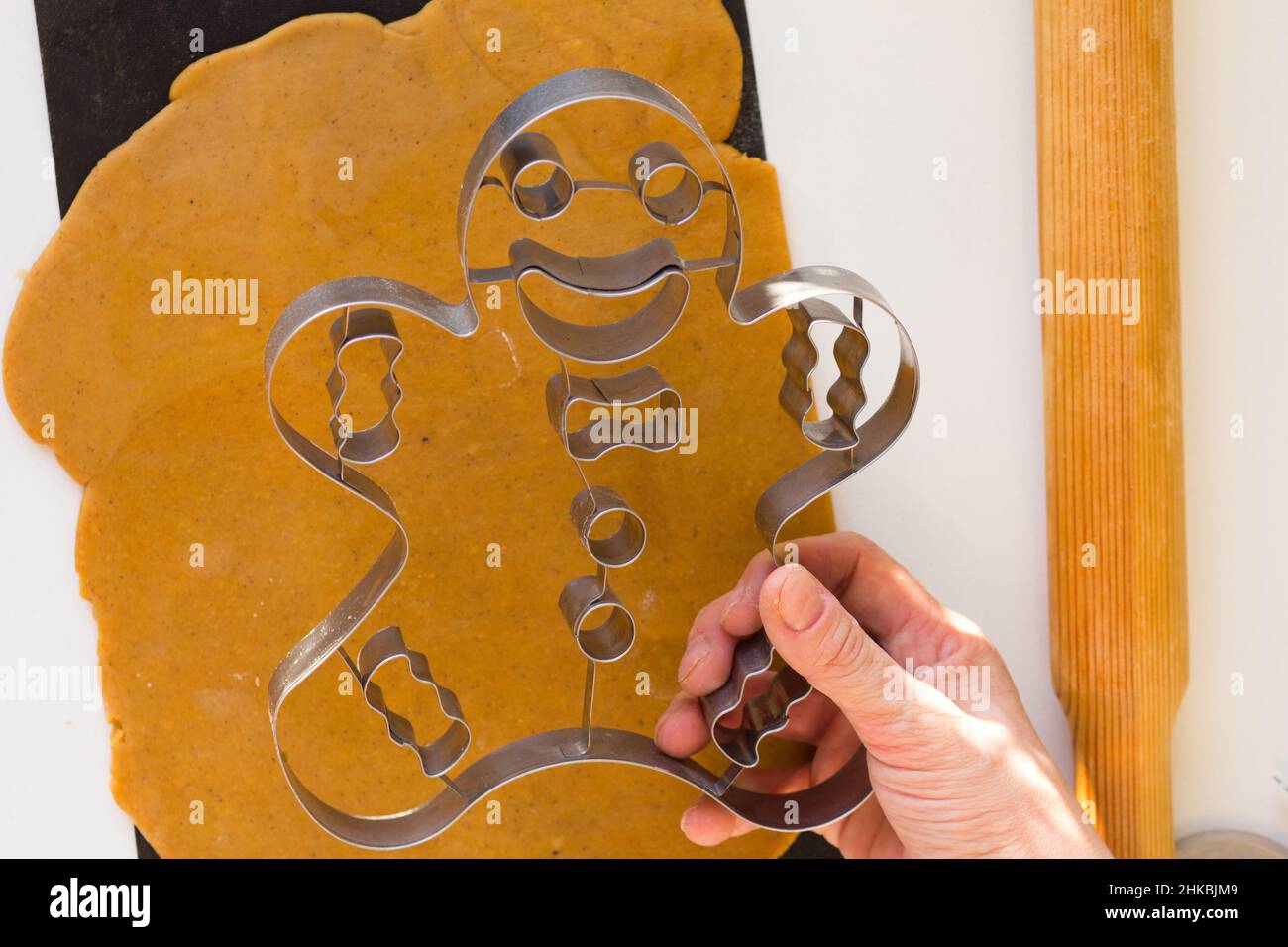 Woman hand holding metal form of gingerbread man before cutting it out ...