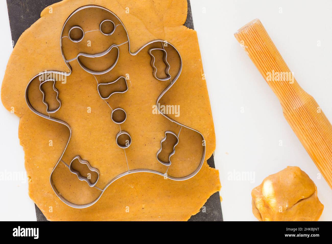 Metal form of gingerbread man on raw dough on black teflon baking sheet ...