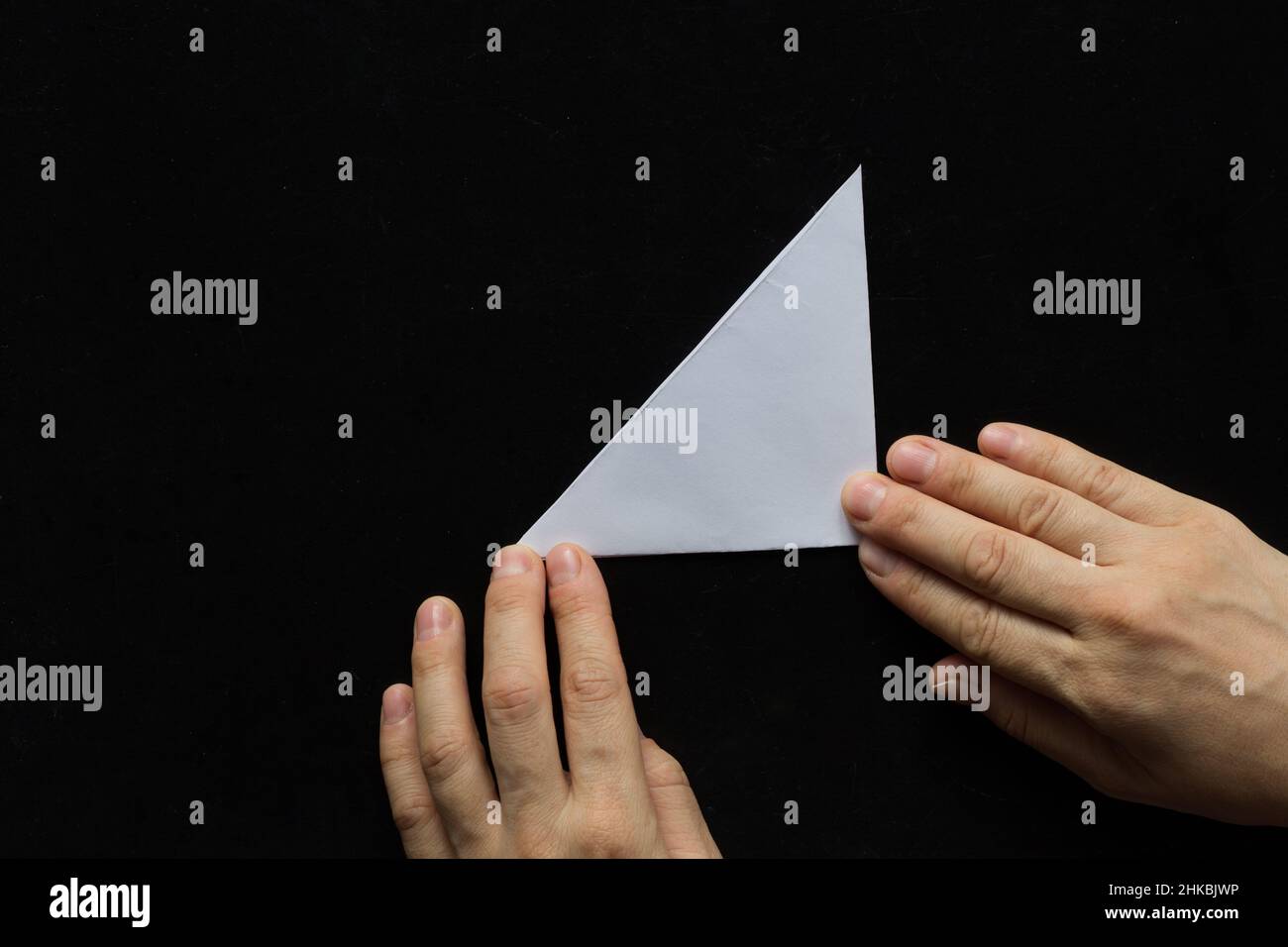 Making snowflake. Step 2. Woman hands holding paper folded small ...