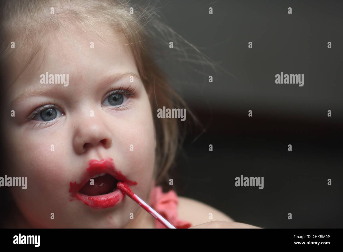 Happy little girl putting red lipstick on lips Stock Photo - Alamy