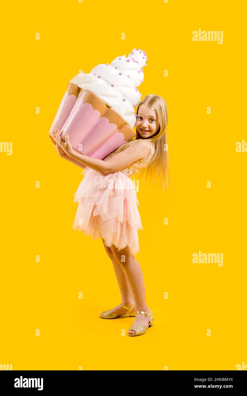 The girl hugs in her hands a huge cupcake, filled with cream ...