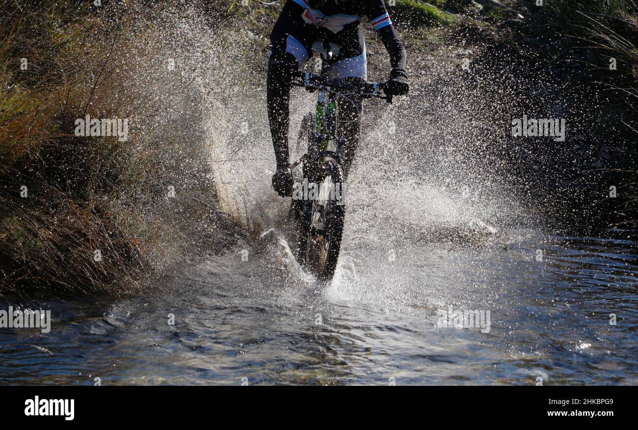 A mountain biker crosses a stream full of water Stock Photo - Alamy