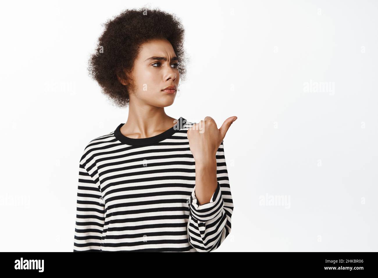 Confused black girl staring and pointing at right side, frowning ...