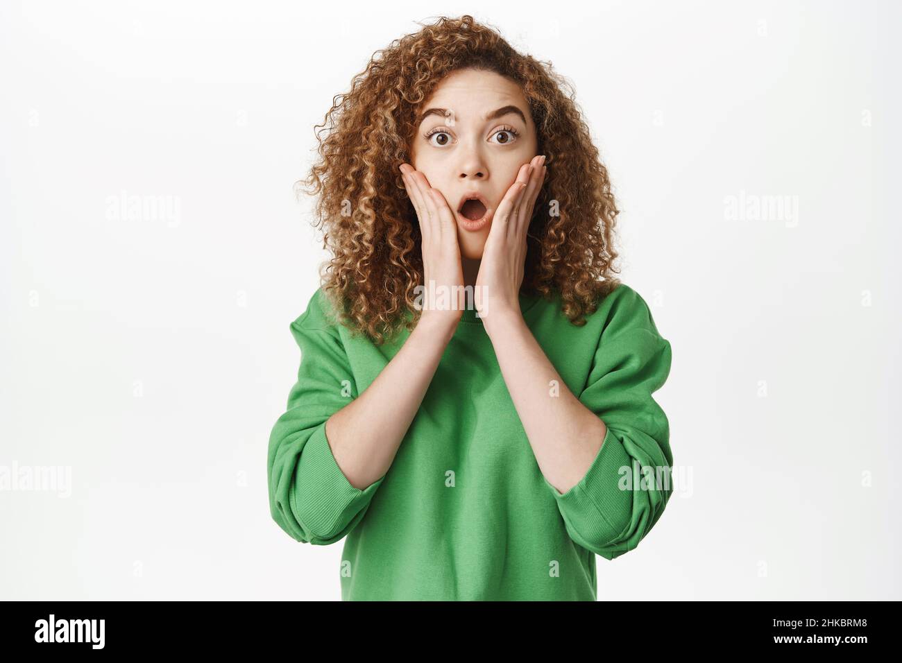 Wow. Amazed curly girl gasping with excitement, staring at camera ...