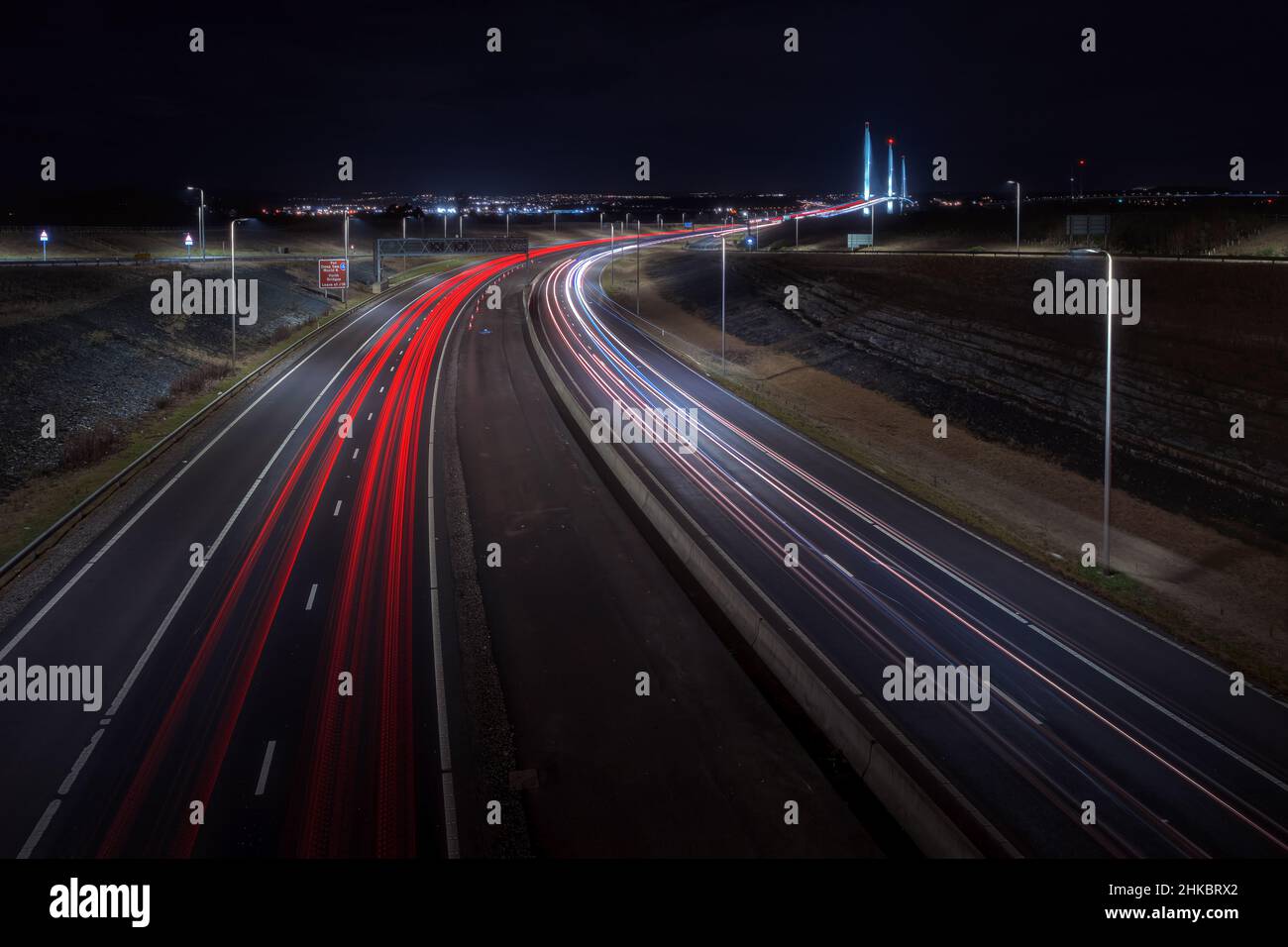 Highway leading to the big bridge and lights from cars at night ...