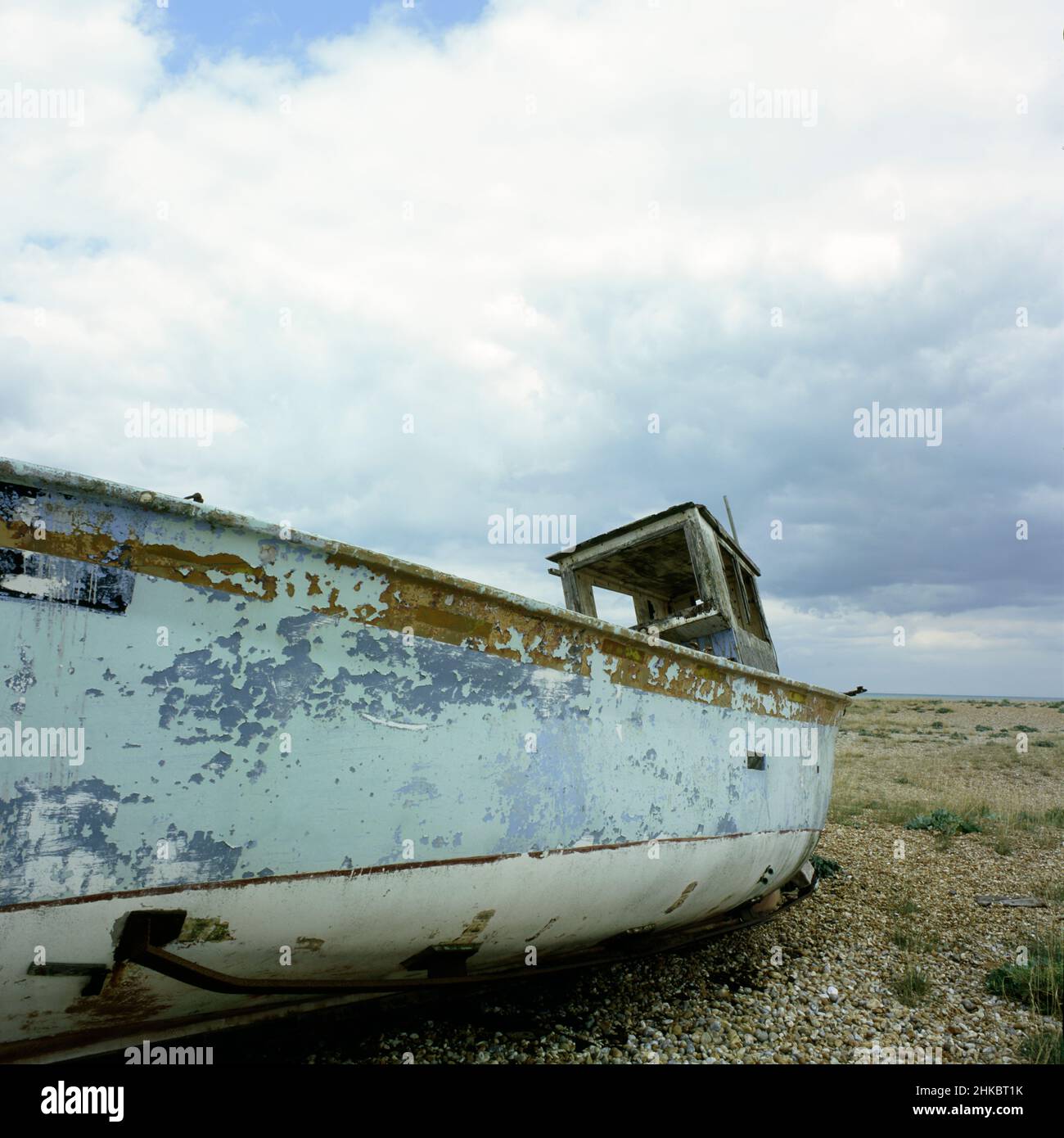 Beached and wrecked boat with peeling paint on the shingle at Dungeness ...