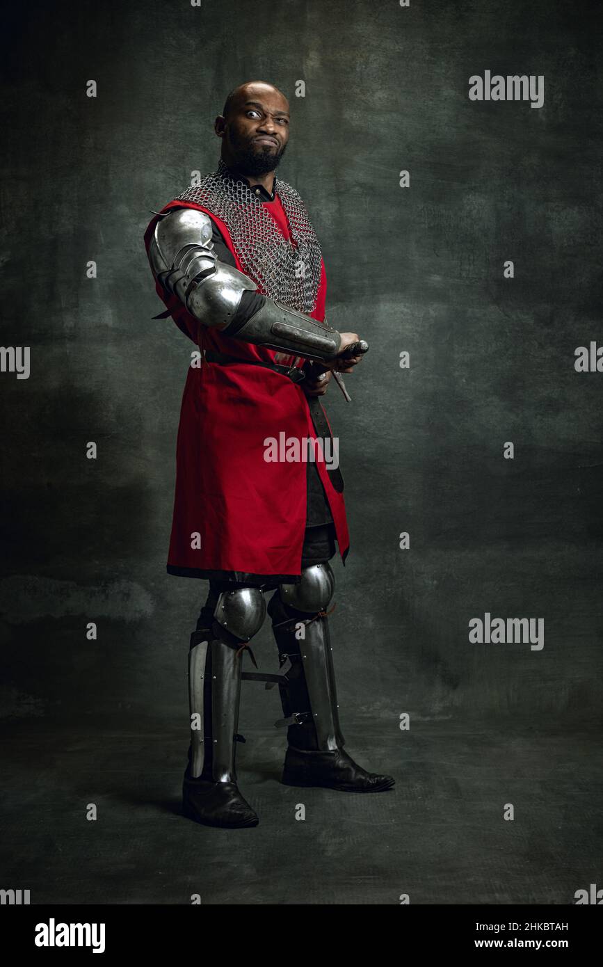 Portrait of cheerful dark skinned man, medieval warrior or knight with ...