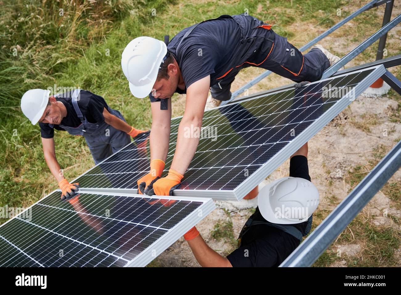 Male workers building photovoltaic solar panel system outdoors. Men ...